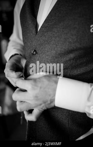The man fasten a button on his jacket. The groom fasten a button on his ...