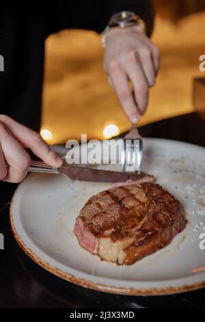 eating stake from plate with fork and knife man hands Stock Photo - Alamy
