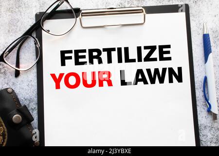 Sign on a green lawn - Fertilize your lawn Stock Photo - Alamy