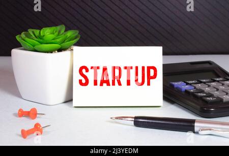 The word STARTUP is written on wooden cubes on a wooden background next ...