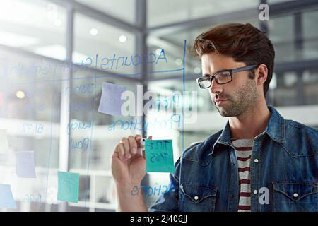 Its all about planning properly. a handsome young man writing in a ...