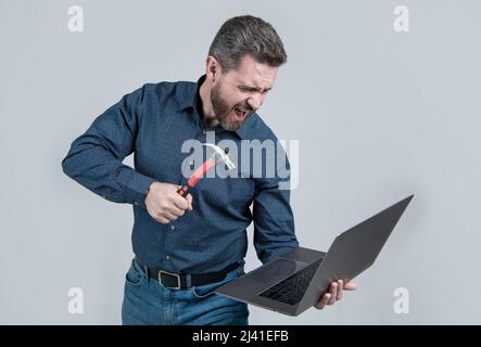 Furious man break laptop hitting notebook with hammer grey background ...