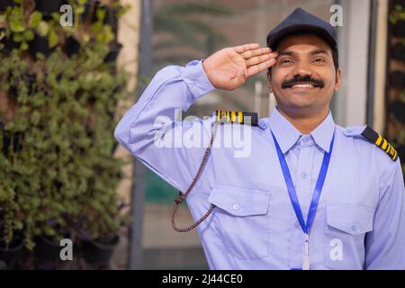 Portrait of security guard saluting while working at gate Stock Photo ...