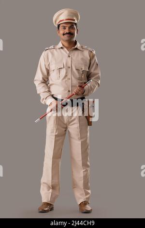 Portrait of an Indian policeman standing with baton in hand Stock Photo ...