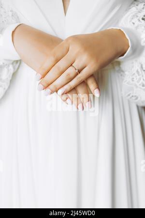 Gentle female hands of the bride with a gold wedding ring on the ring ...