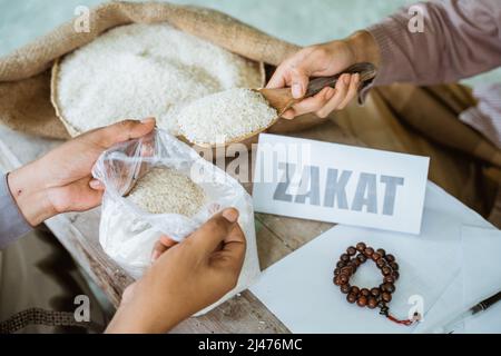 Hands giving rice grains for zakat helping the poor Stock Photo - Alamy