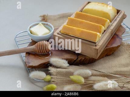 Slices of four butter cakes in wooden box served with butter and honey ...