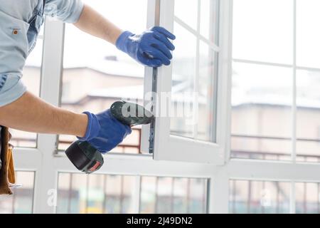 handyman adjusting white pvc plastic window indoors. worker using ...