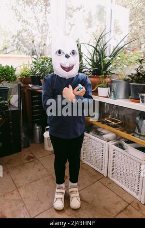 Girl celebrating Easter with a rabbit mask, arms crossed and some ...