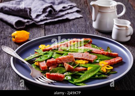 hot salad of fried sugar snap peas with tuna slices, pepper, thyme on a ...