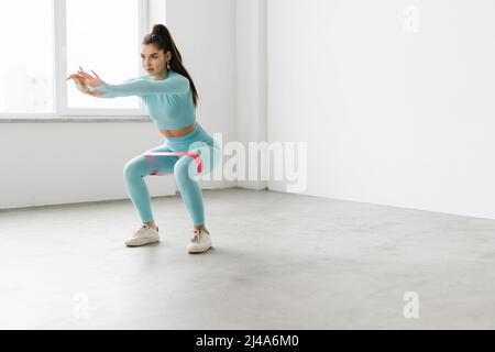 Athletic girl doing squats with resistance bands Stock Photo - Alamy