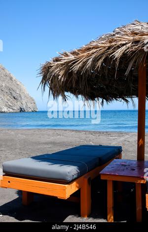 A sun umbrella at the famous sandy black beach of Perissa Santorini ...