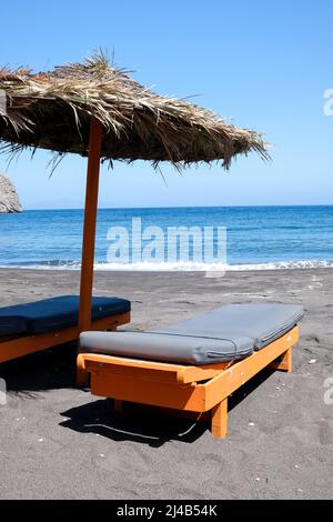 A sun umbrella at the famous sandy black beach of Perissa Santorini ...