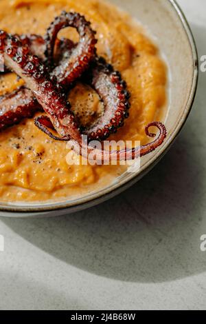 Close up of delicious grilled octopus and hummus served for lunch or ...