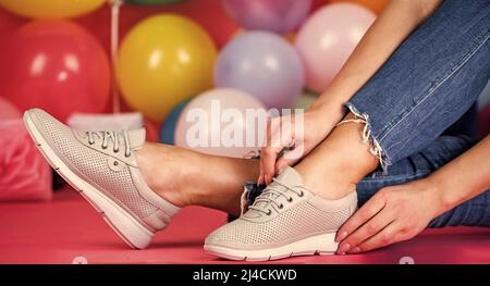 female feet in sporty comfortable shoes with laces at colorful balloons ...