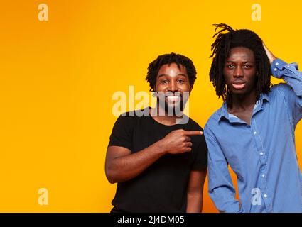 two african american guys posing cheerful together on yellow background, lifestyle people ...