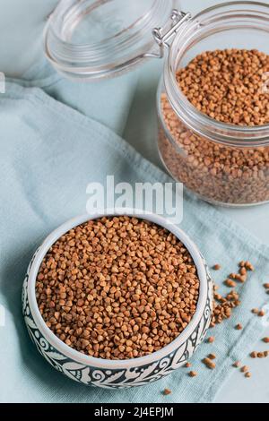 Organic uncooked scattered buckwheat grain in a bowl on a rustic wooden ...