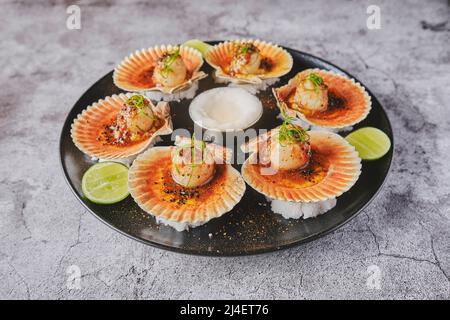 Scallops with flamed shells on a black plate. Luxury restaurant food ...