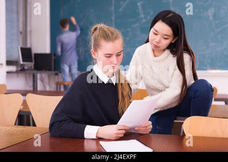 Classmate comforting upset asian girl student Stock Photo - Alamy