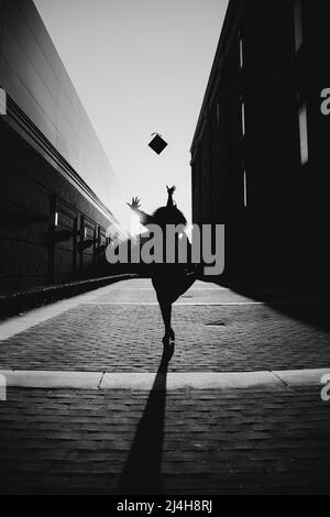 Black woman standing strong and tossing graduation cap in the air ...