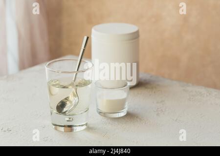 Glass with collagen dissolved in water and collagen protein powder on ...