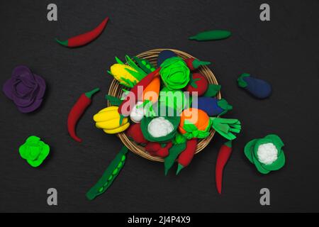 Basket of plasticine vegetables and fruits on a black background. Fresh ...