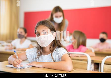 Teacher helping kids to complete exercises Stock Photo - Alamy