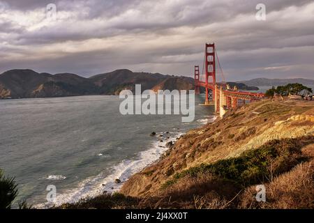 Wide angle view of Golden Gate Bridge against stormy sky at sunset ...