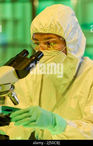 Young serious female virologist in protective mask and gloves studying ...