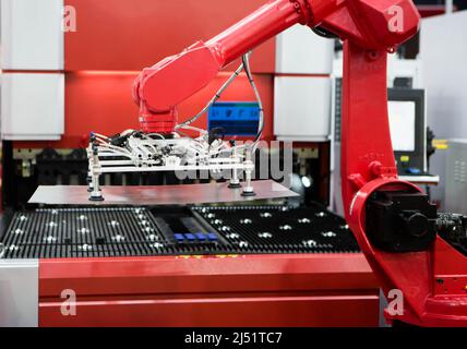 Robot arm loading metal sheet to laser cutting machine in production ...