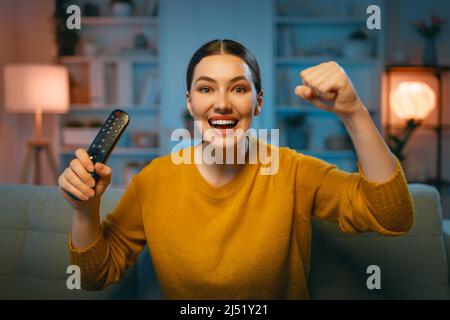 Young woman watching projector, TV, movies and eating popcorn in the ...
