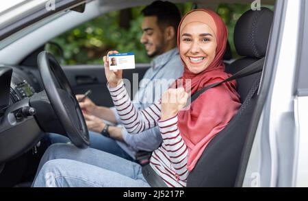 Glad muslim woman in hijab show driving license and fist in open door ...