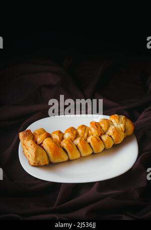 Homemade braided bread filled with strawberry jam on a white plate with ...