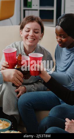 Cheerful coworkers cheers with cups and bottles of beer after work at ...