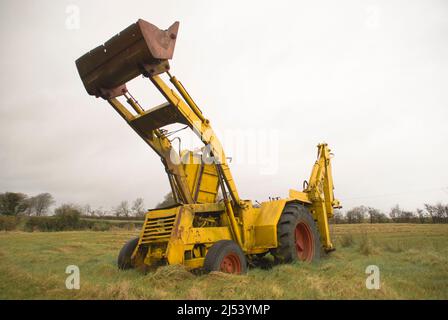 In the middle of a rural farm, a backhoe loader is building terraces ...
