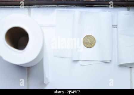 Roll of white toilet paper and golden Ukrainian hryvnia coin ...