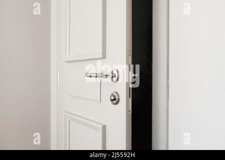 White bathroom door left ajar, slightly open doorway with modern handle ...