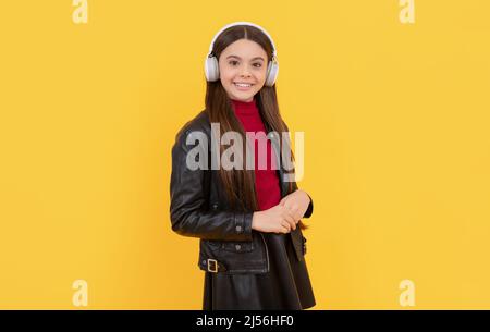 positive teen girl listen music in headphones on yellow background ...