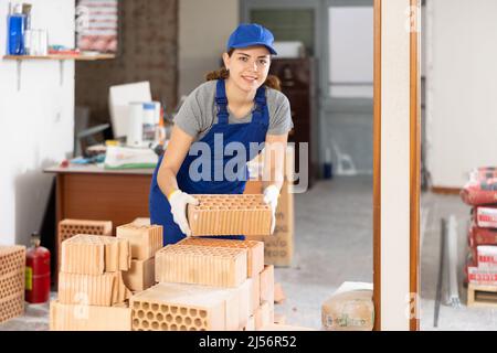 Young woman builder stacking bricks in building site Stock Photo - Alamy