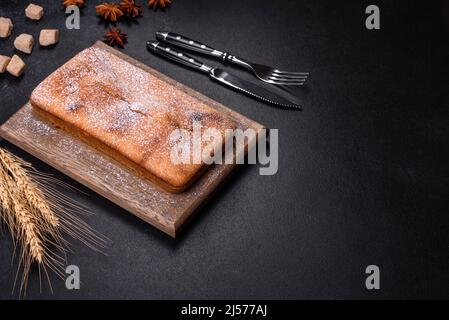 Baked rectangular cupcake with raisins and chocolate on a dark concrete ...