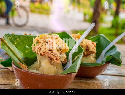 Vigoron with leaves served on a wooden table, two vigorones served on ...