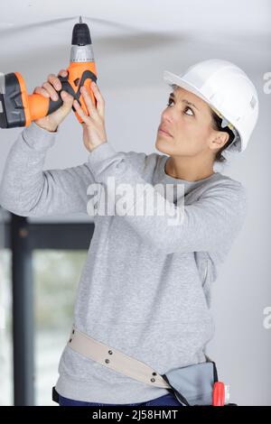 Female contractor drilling into ceiling Stock Photo - Alamy