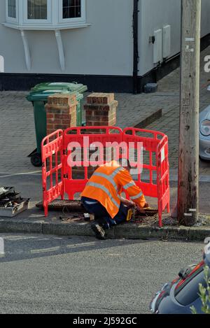 Openreach engineer working on pavement sited telephone junction box ...