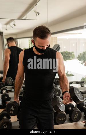 New normal concept. Young athletic man wearing a prevention face mask ...