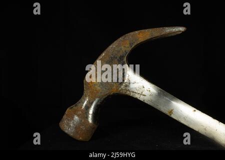 rusty hammer head and shaft with head down isolated on a black ...