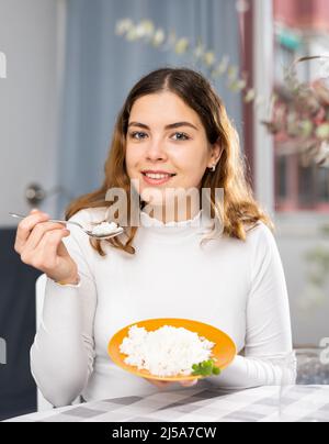 Emotional young woman eating rice at home Stock Photo - Alamy