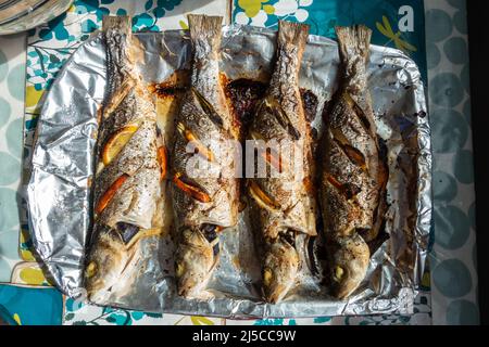Four fish baked on a tray covered with aluminium foil Stock Photo - Alamy