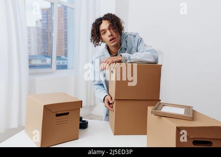 guy with curly hair unpacking things from boxes in the room sorting ...