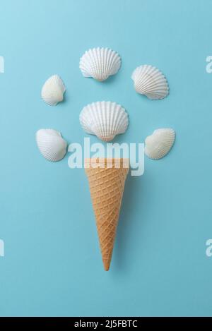 Ice cream cone with sea shells and starfish over blue background ...