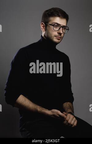Young intelligent man wearing turtleneck and eyeglasses on gray ...